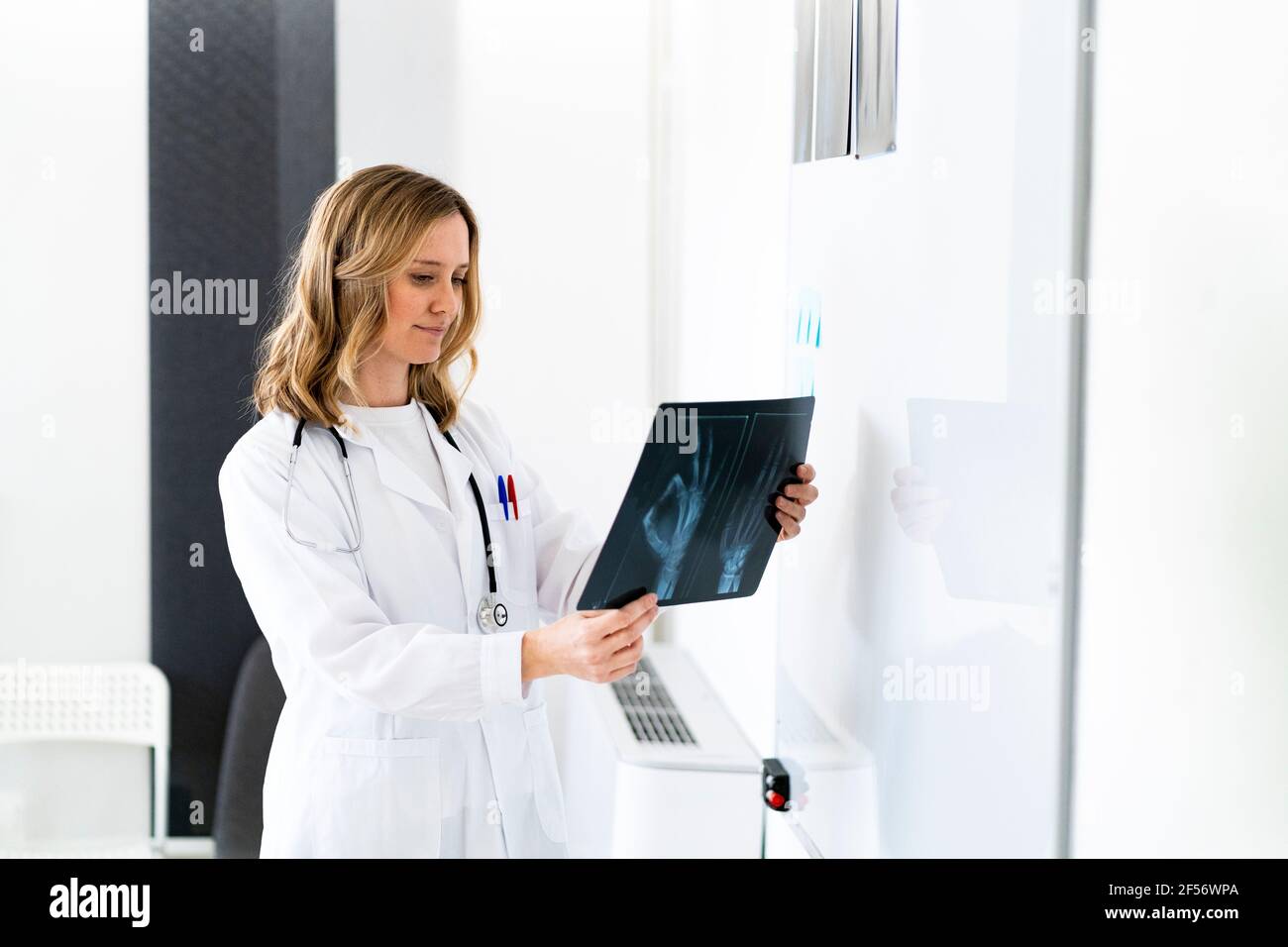 Blond female radiologist examining X-ray at medical clinic Stock Photo ...