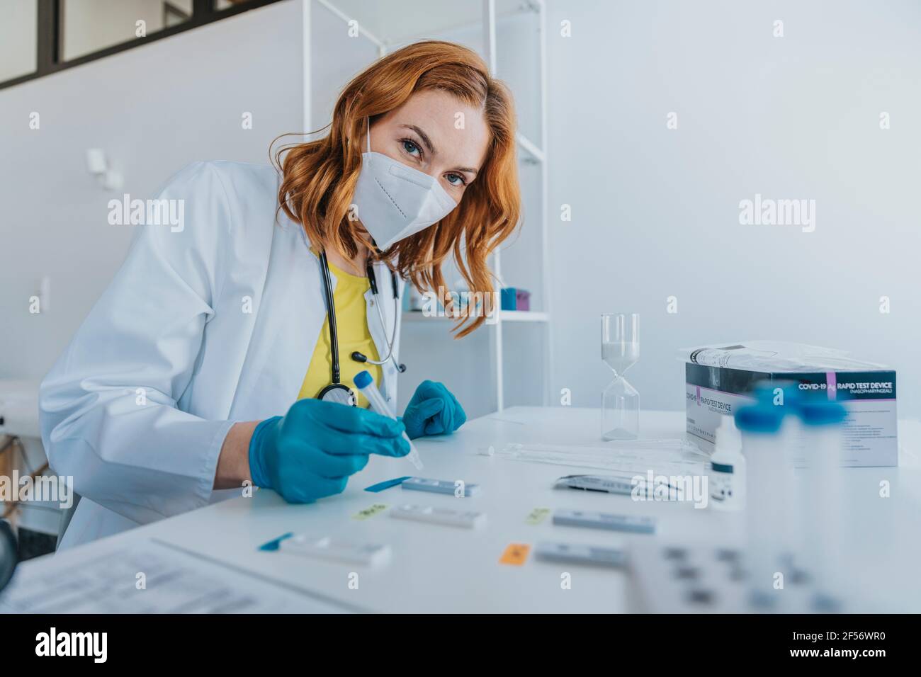 Doctor wearing protective face mask testing sample on test cassettes at ...