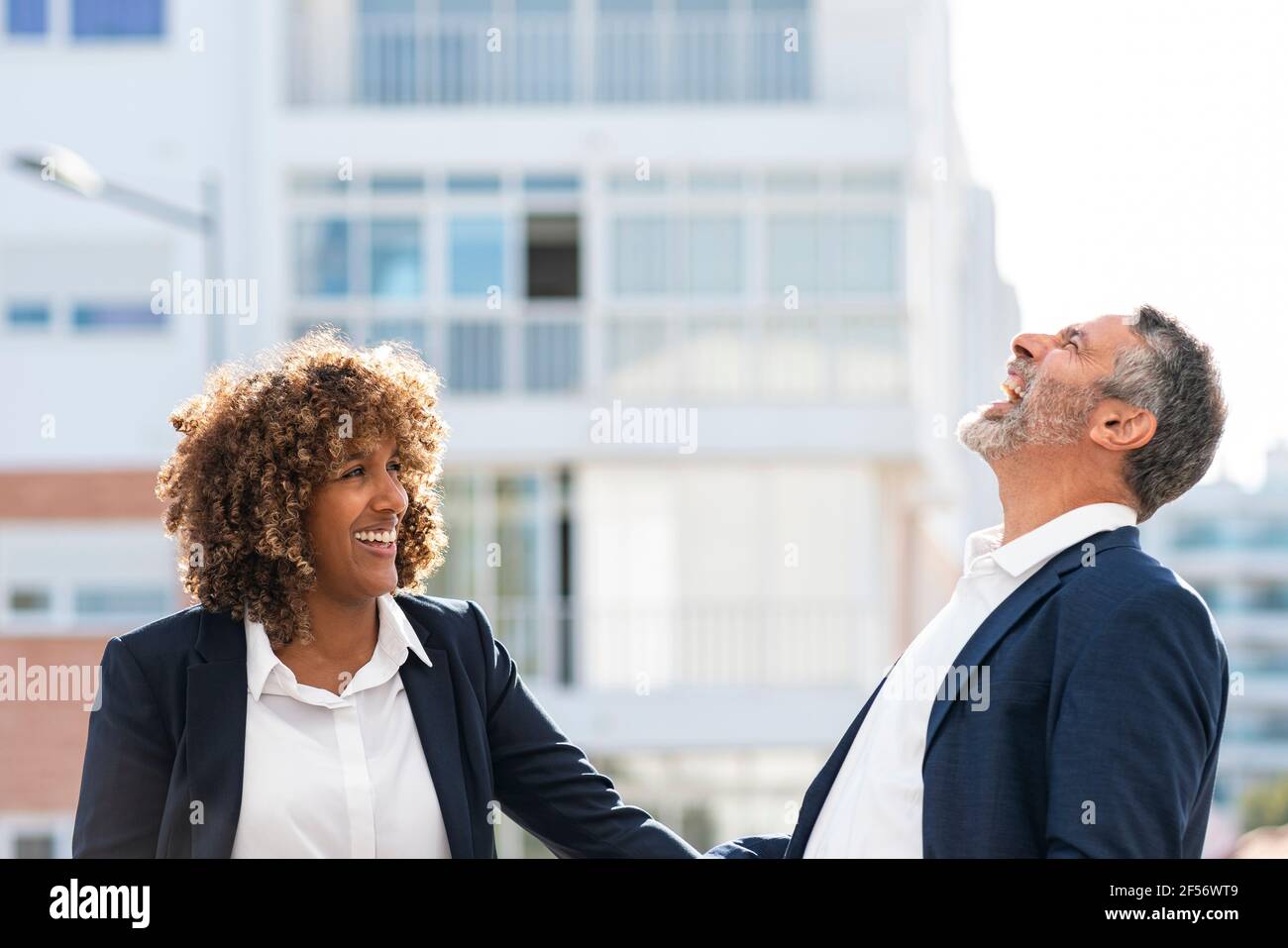 Happy business people laughing while standing outdoors Stock Photo - Alamy
