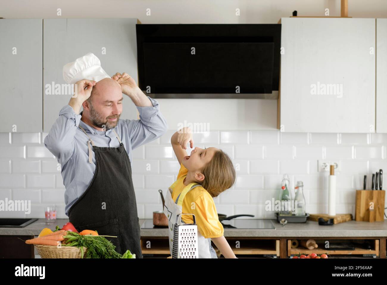 Father wearing chef's hat while standing by daughter at home Stock ...