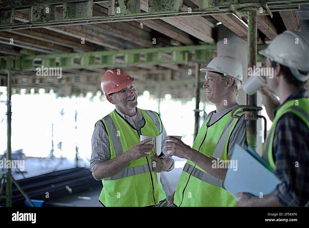 Smiling construction workers discussing at construction site Stock ...