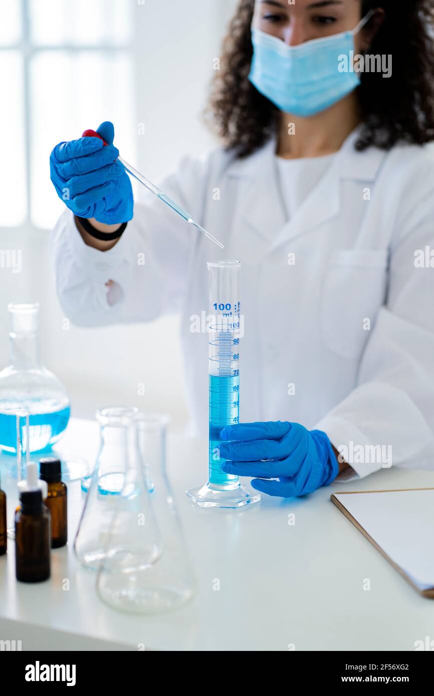 Female researcher mixing chemical solution in test tube through pipette ...