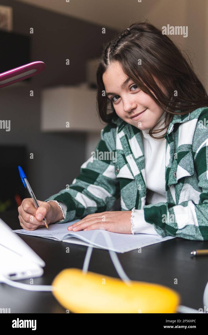 Smiling girl studying at table in living room Stock Photo - Alamy