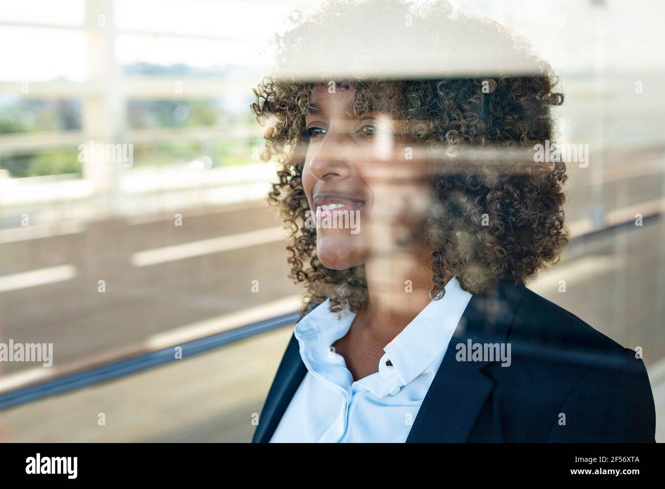 Female entrepreneur looking through window while standing at modern ...