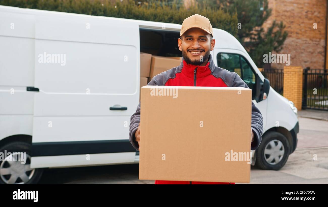 Young indian man delivering parcel. Giving cardboard box. High quality ...