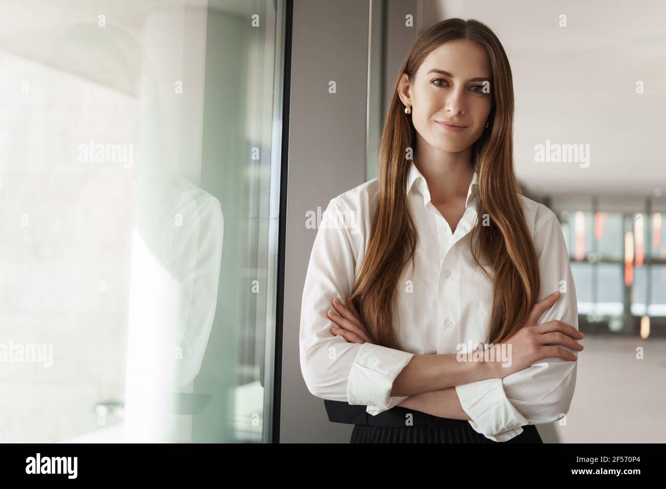 Pleasant young female assistant, manager standing in office corridor ...