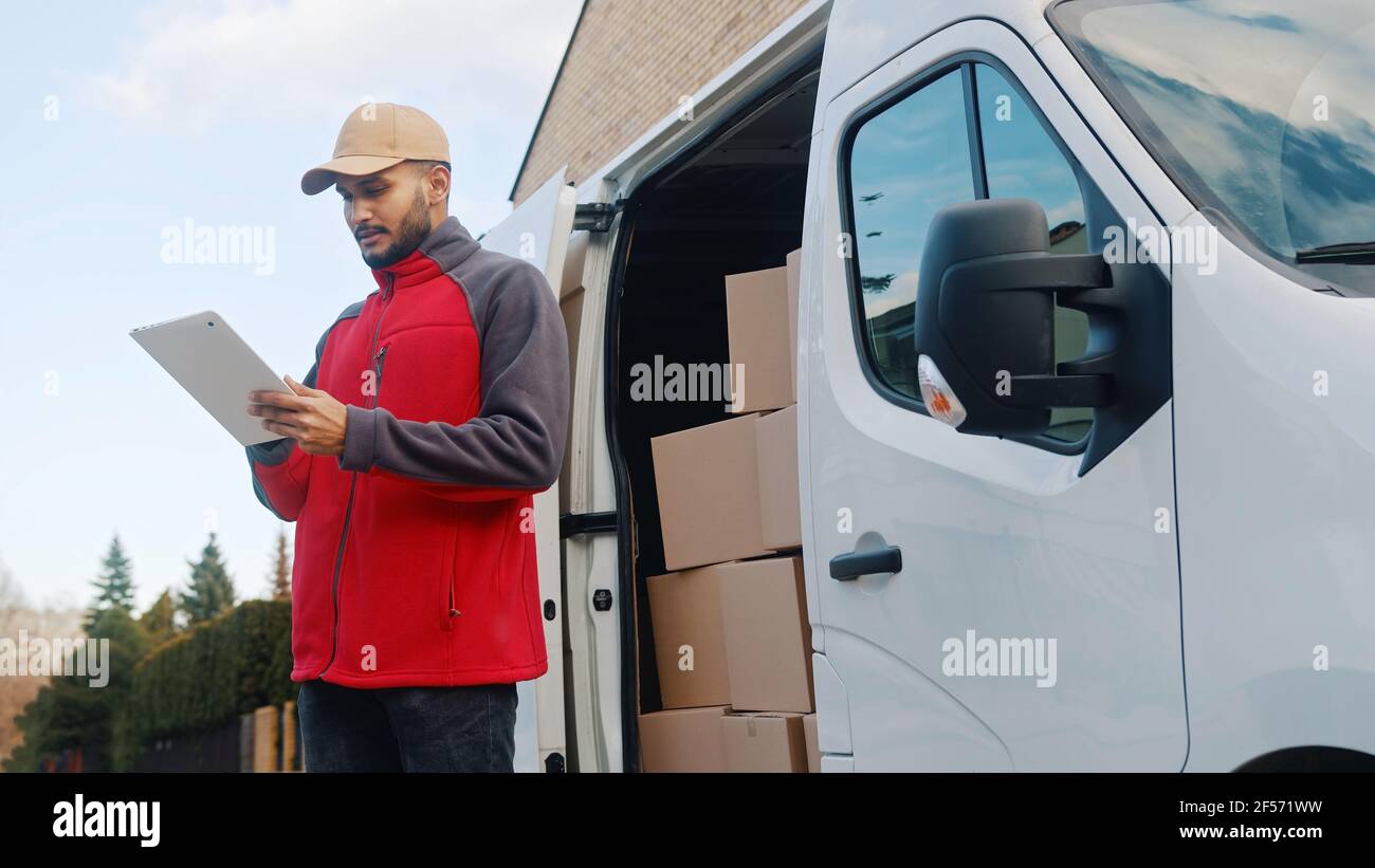Young delivery man using tablet to find the address and deliver parcel ...