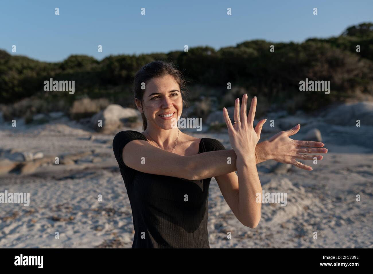 Young woman in sportswear doing stretching exercises for neck and arms ...