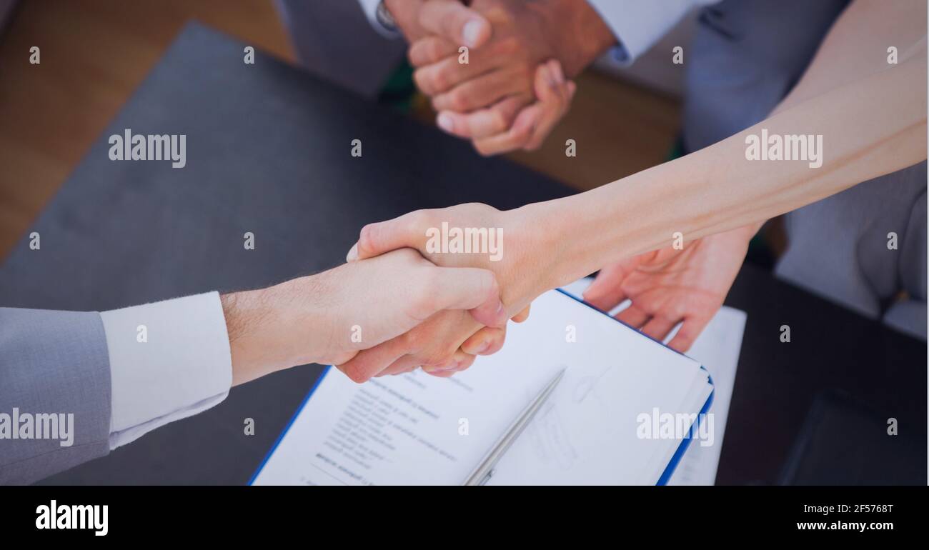 Businesswomen shaking hands over desk in office Stock Photo - Alamy