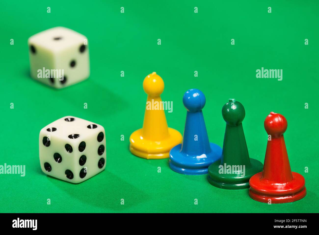 Game pieces of different colors and dice Stock Photo - Alamy