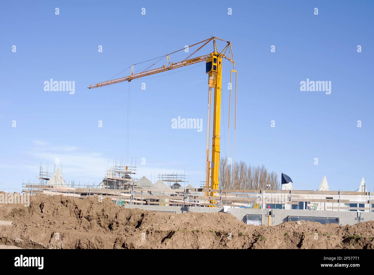 Skeleton of a building under construction with a large yellow crane ...