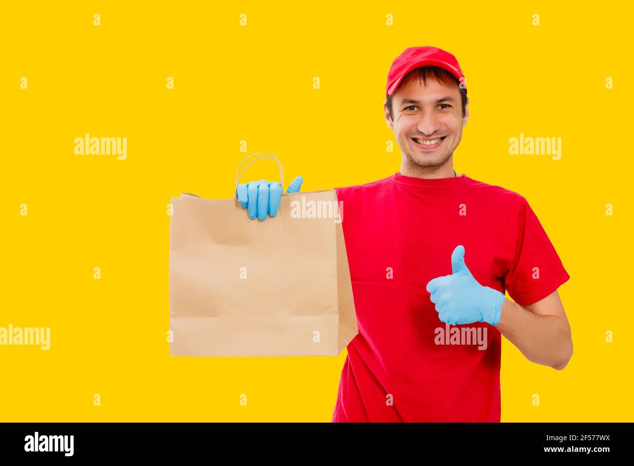 Portrait of delivery man in red uniform holding parcel box isolated ...
