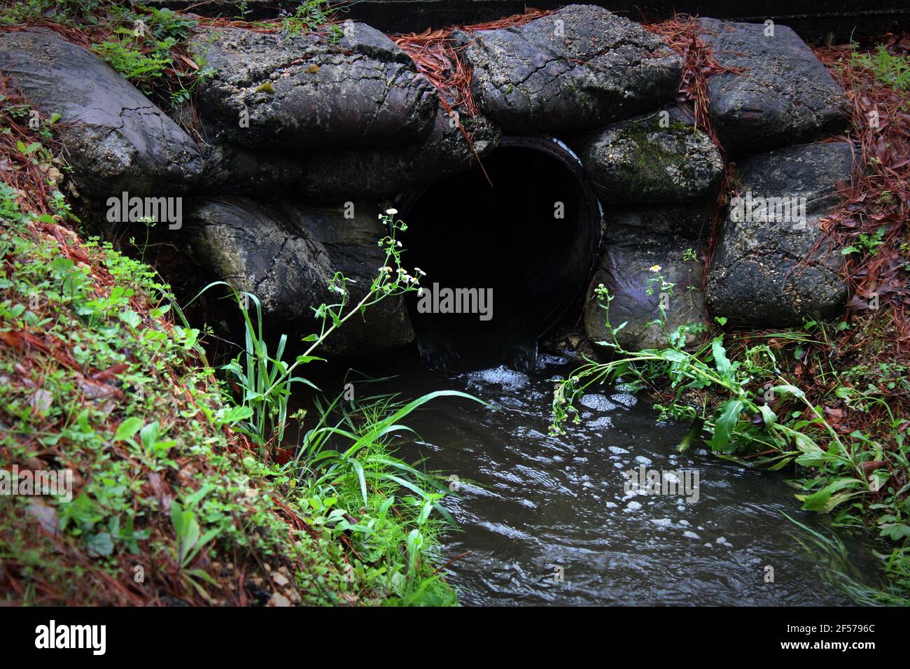 water flows through a cobblestone drain pipe Stock Photo - Alamy