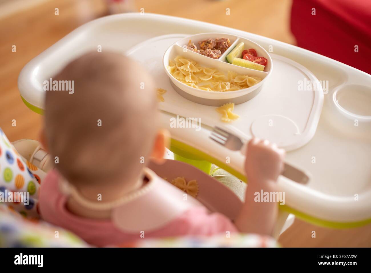 One year old girl having balanced meal in baby eating chair, healthy ...