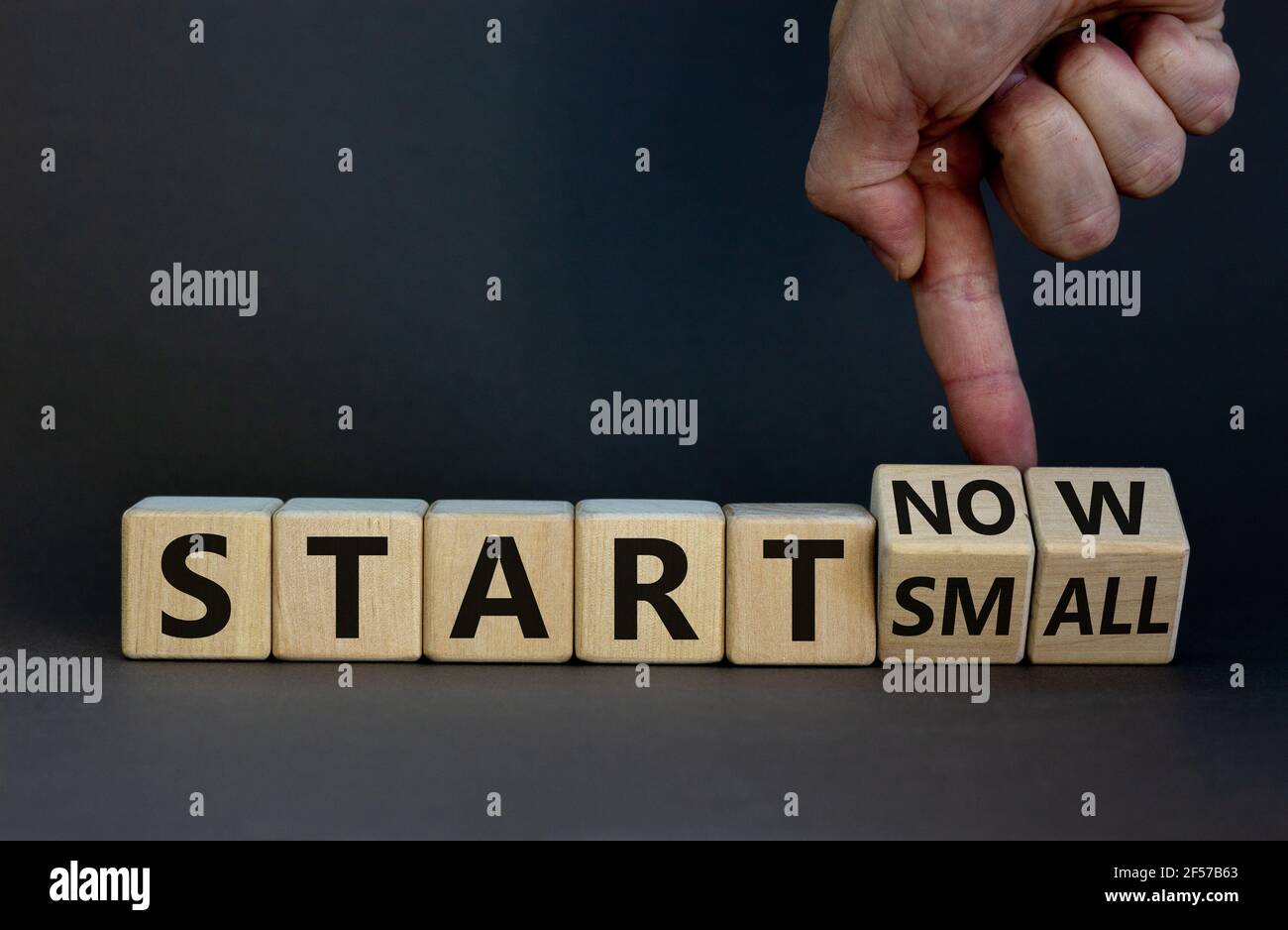 Start small and now symbol. Businessman turns wooden cubes and changes ...