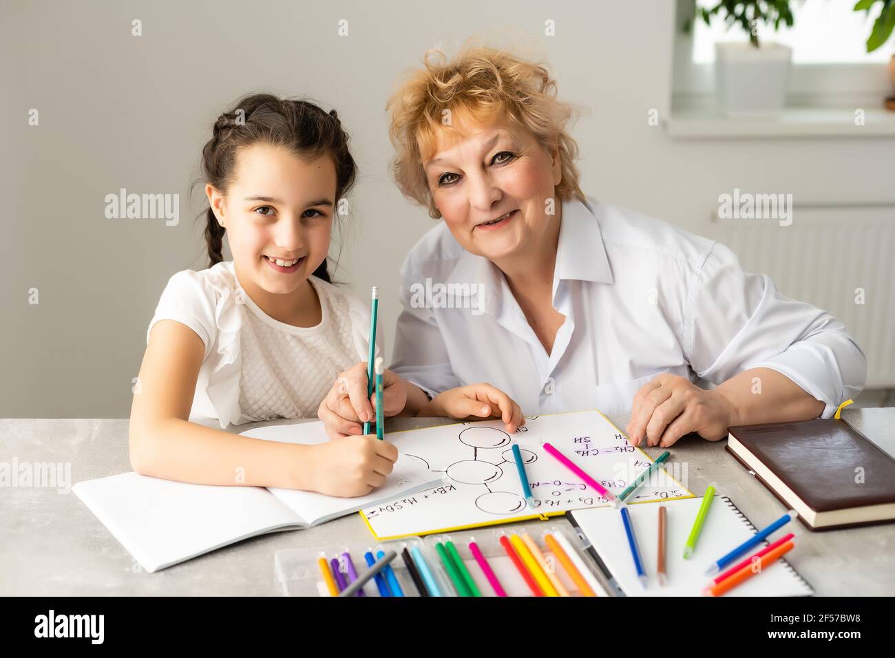 Woman tutor or foster parent mum helping cute caucasian school child ...