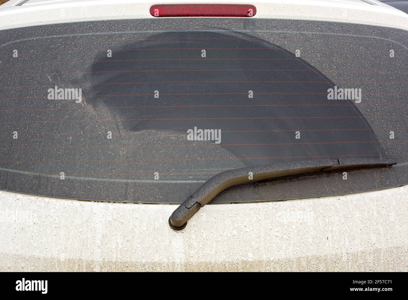 rear window of a white car covered with a layer of dust after rain ...