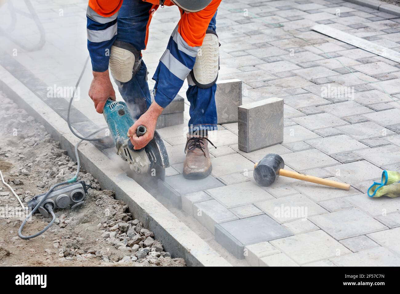 The bricklayer uses a grinder and diamond cutting discs to cut off the ...