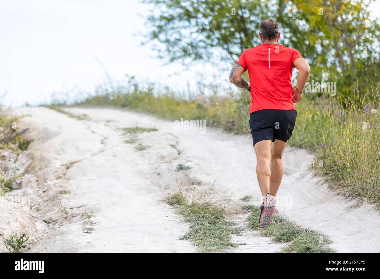 Sporty bearded man running on the path at hillside Stock Photo - Alamy