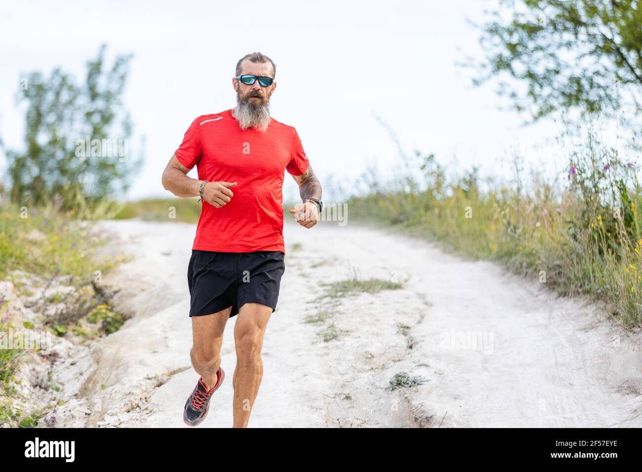Sporty bearded man running on the path at hillside Stock Photo - Alamy