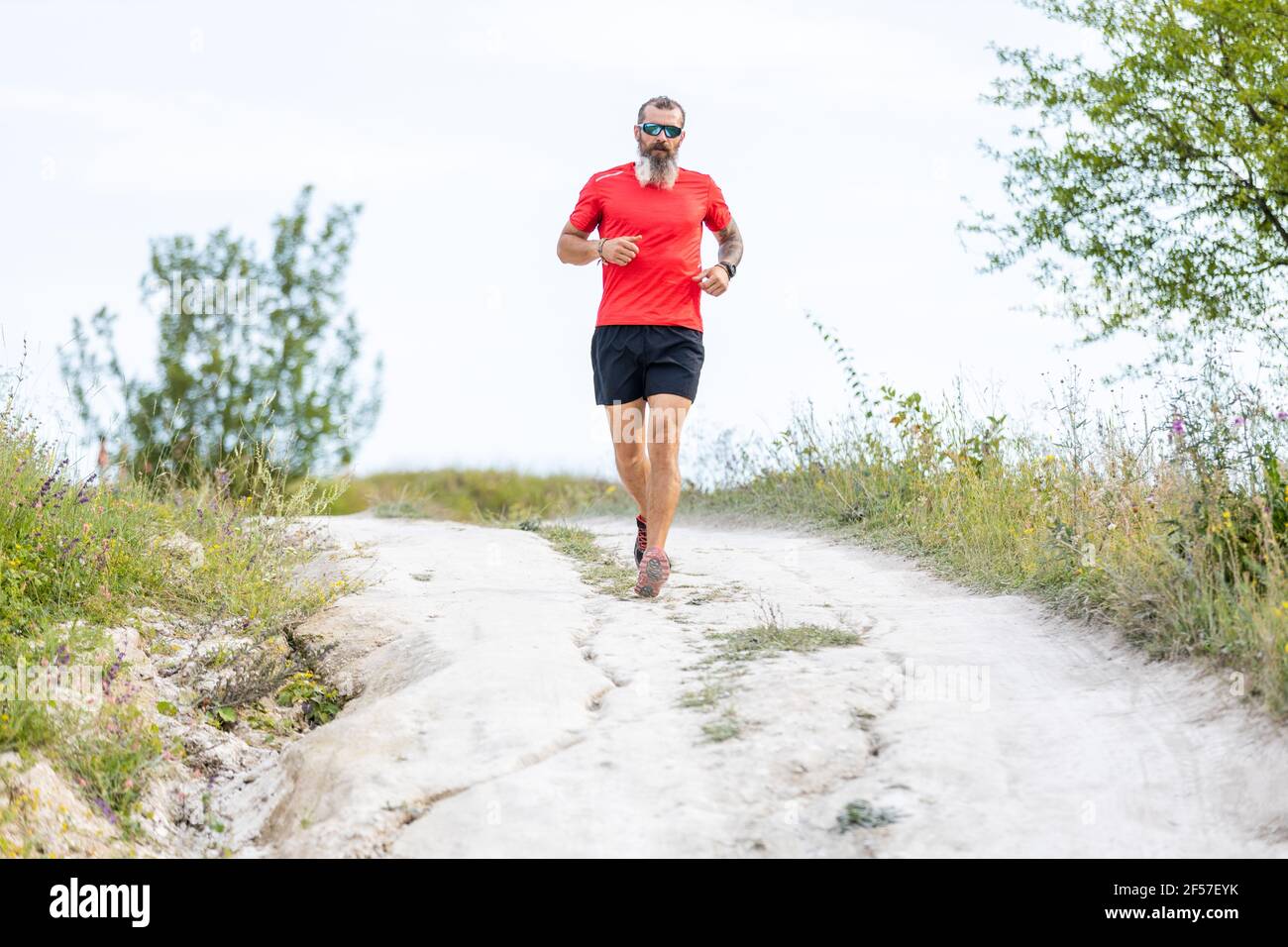 Sporty bearded man running on the path at hillside Stock Photo - Alamy