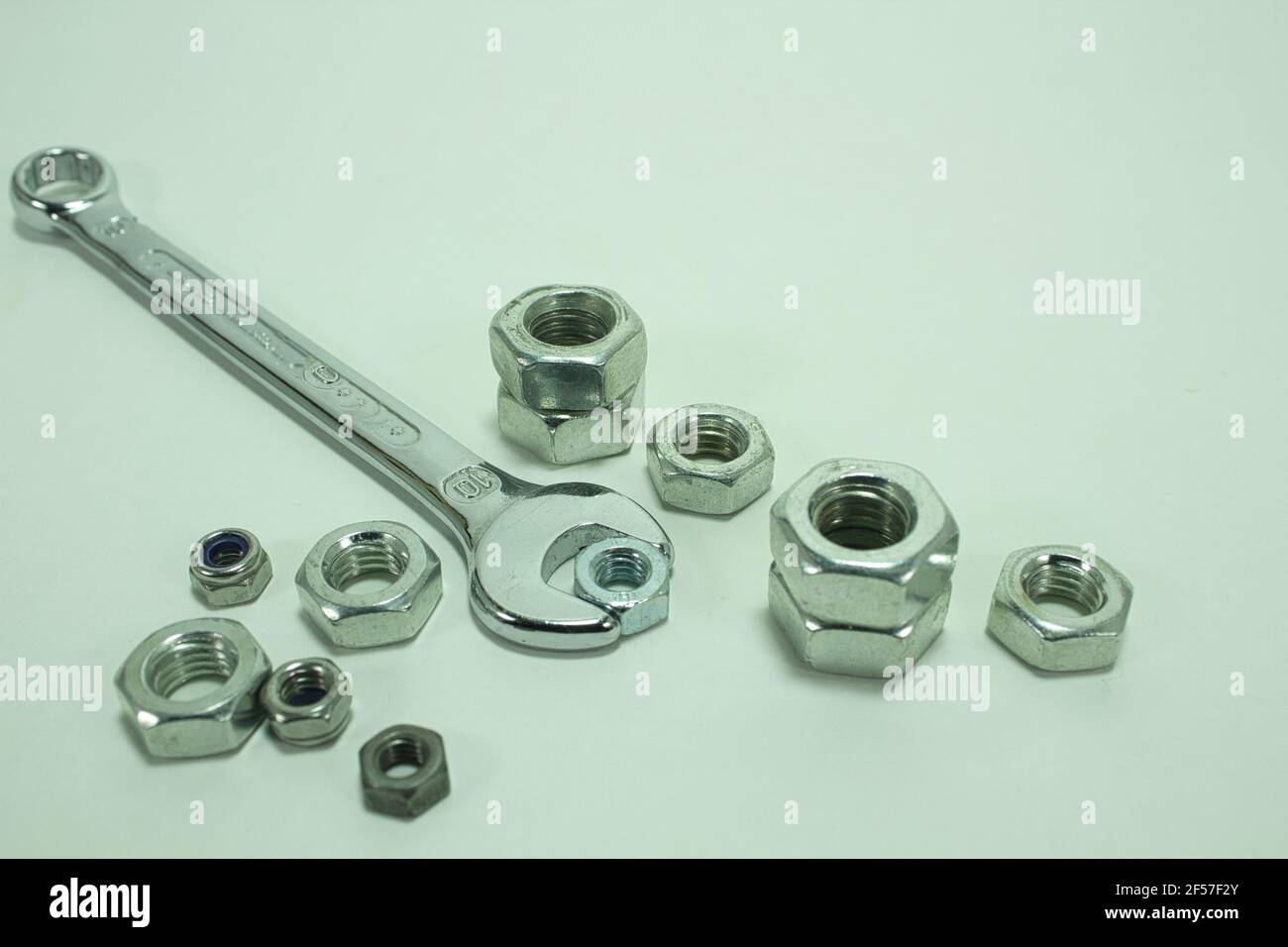 High angle shot of nuts and bolts with a spanner on a white background ...