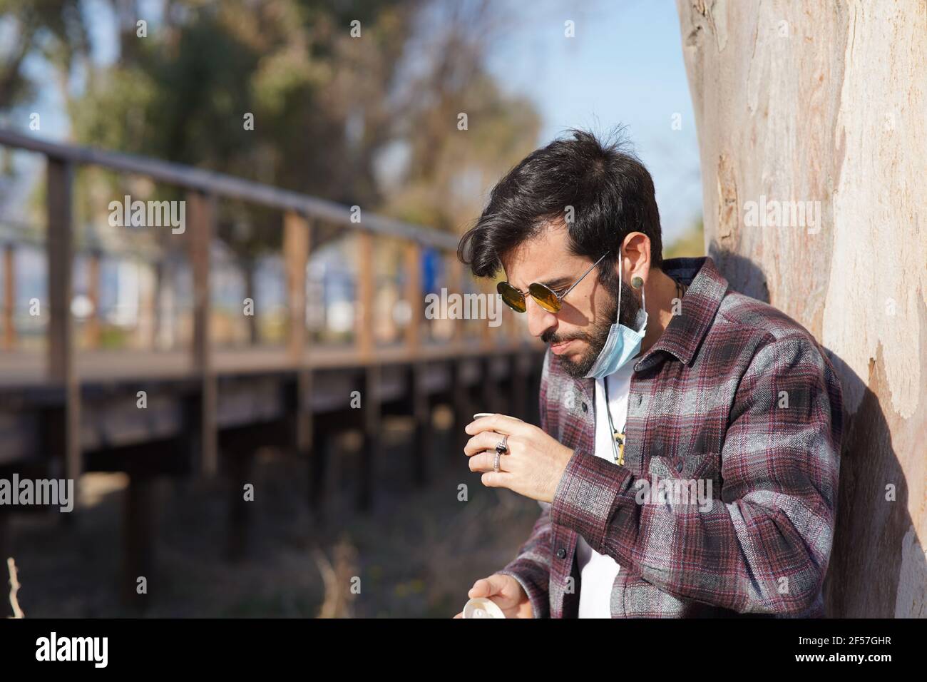 Young cool male in a street style outfit and sunglasses posing outdoors ...