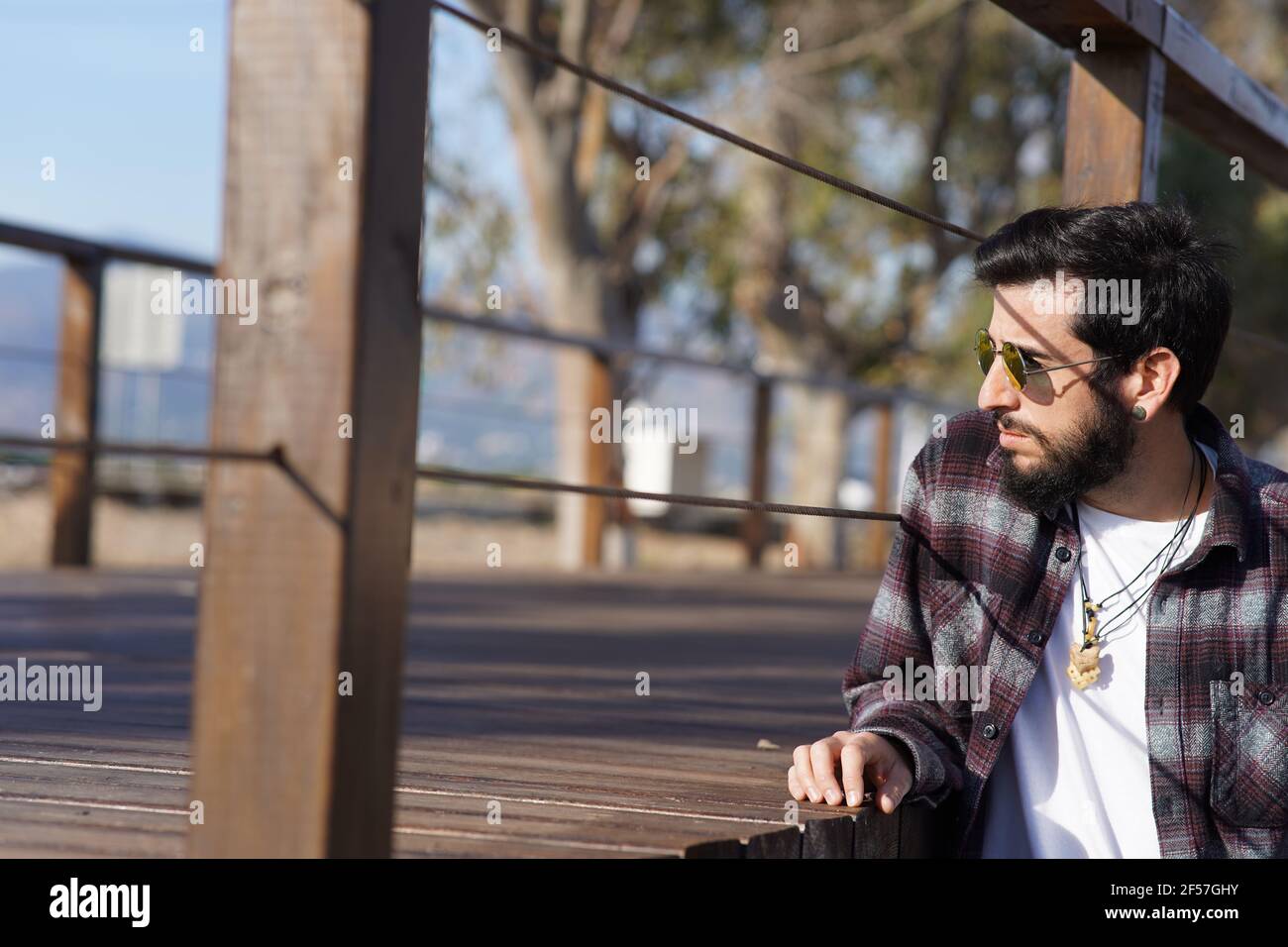 Young cool male in a street style outfit and sunglasses posing outdoors ...