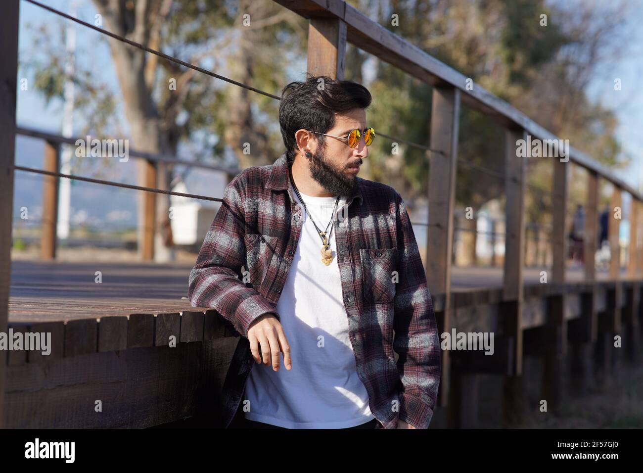 Young cool male in a street style outfit and sunglasses posing outdoors ...