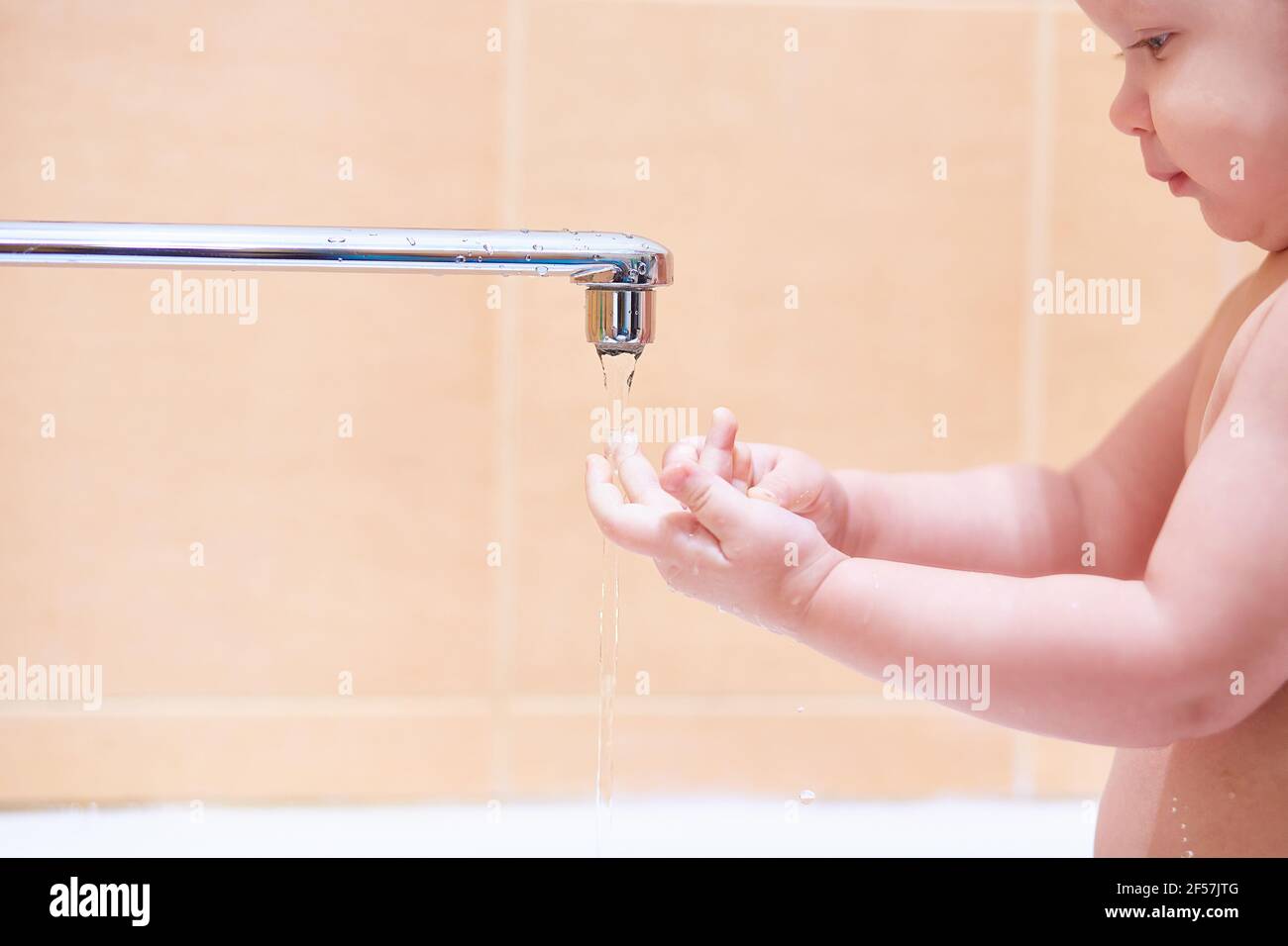 Toddler washes under the tap with running water. Lifestyle In bathroom ...