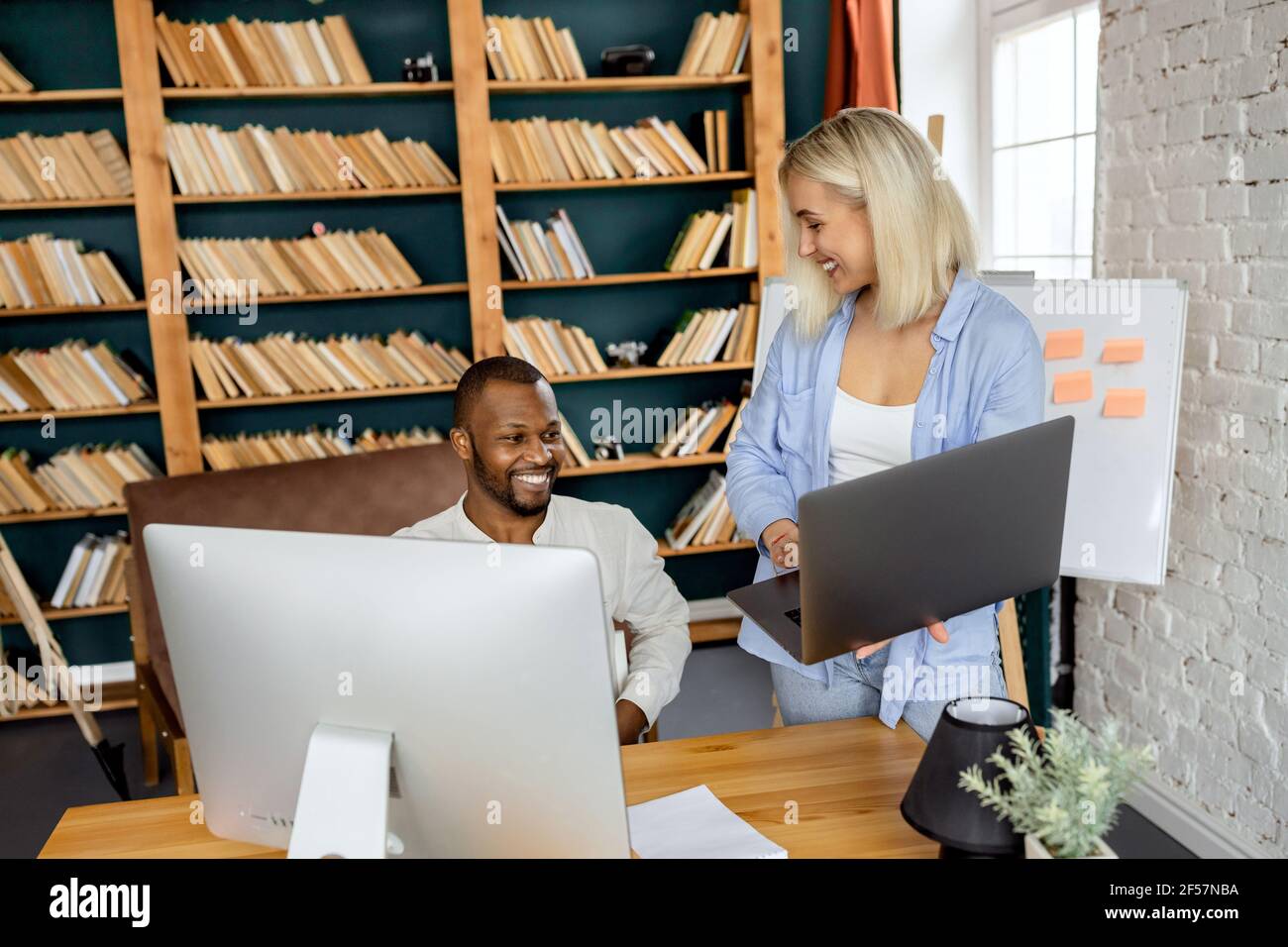 Happy friendly coworkers using laptop, smiling, working together in ...