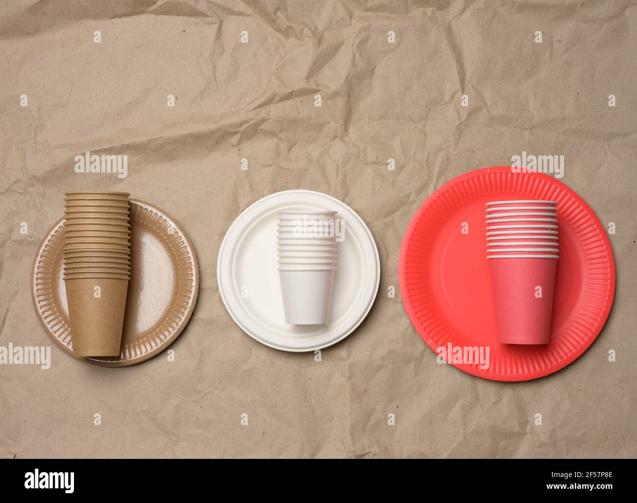 stack of paper cups and round plates on a brown paper background ...