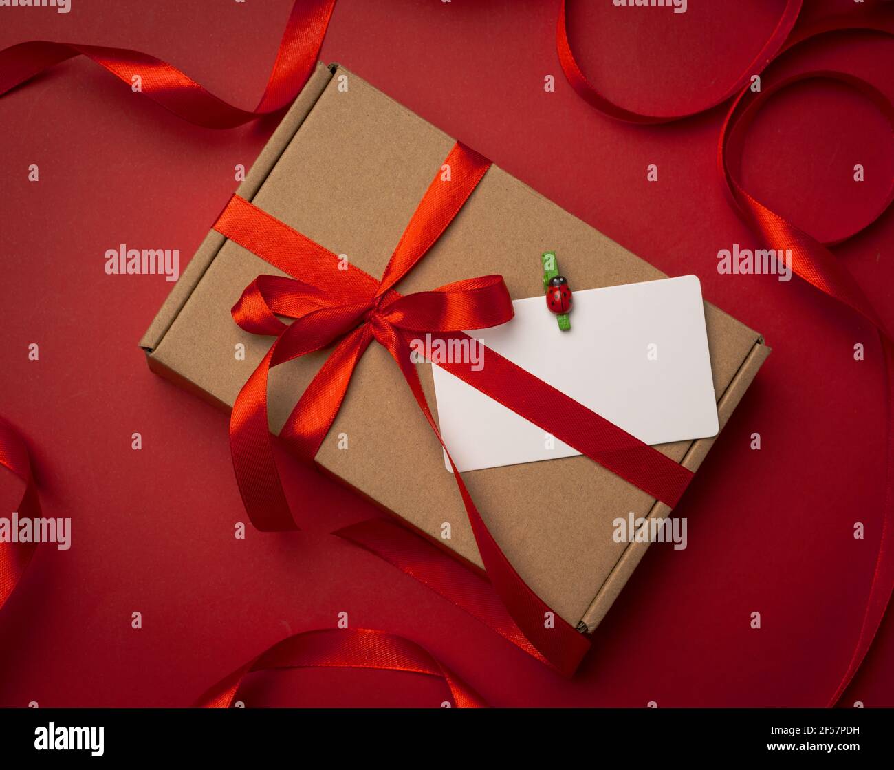 rectangular brown cardboard box tied with a silk red ribbon on a red ...