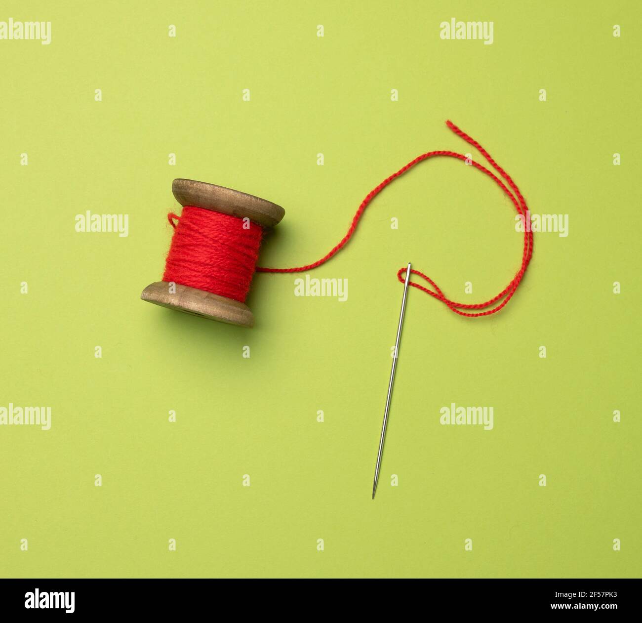 wooden spool with red wool thread on a green background, top view Stock ...