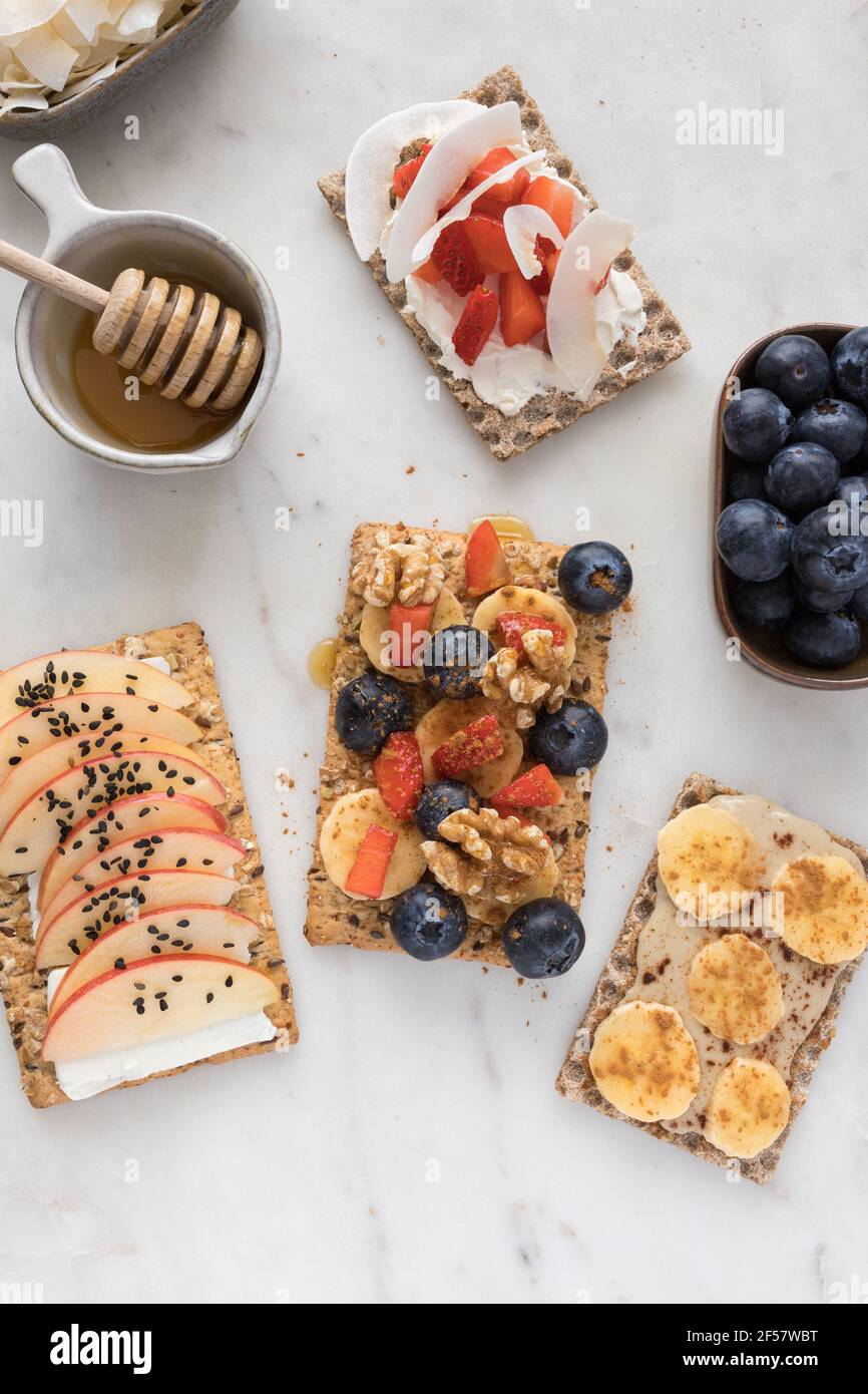 Overhead view of four delicious crackers with fruit, nuts and spices ...