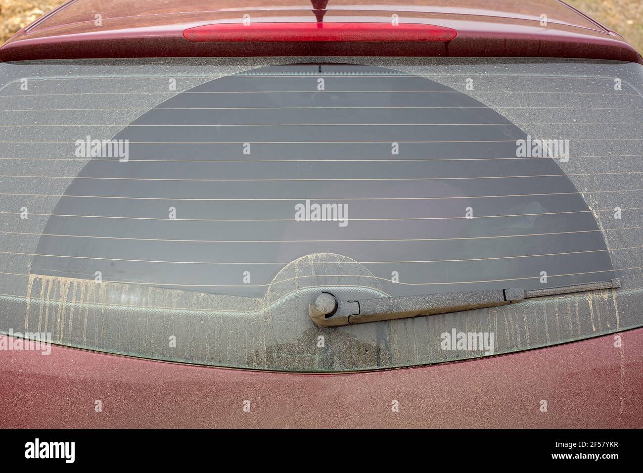 back window of a red car covered with a layer of dust and swipe wiper ...