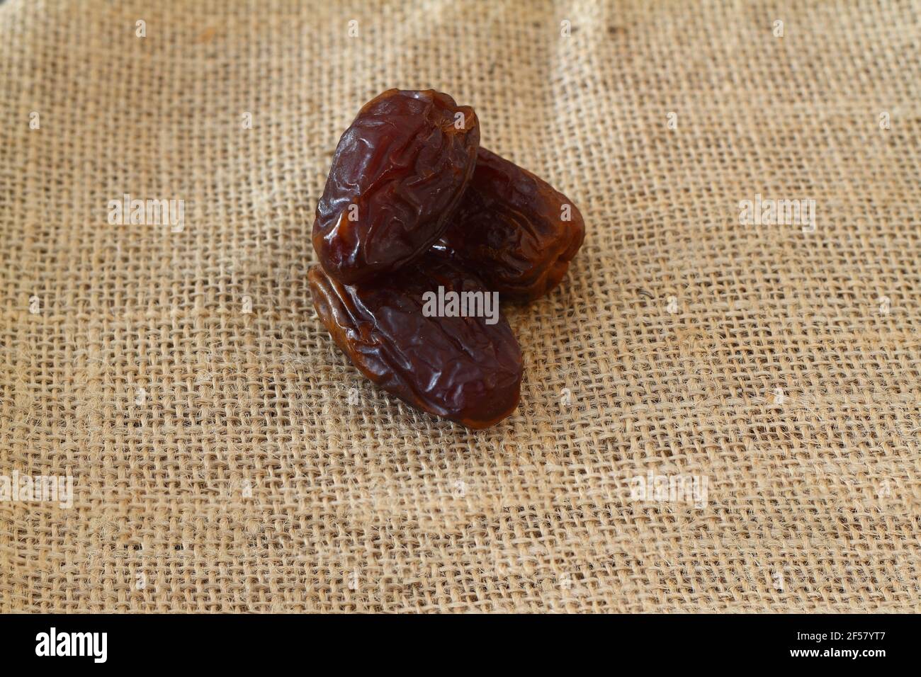 Dates on a sack background. Dried fruits. Dried dates lie next to each ...