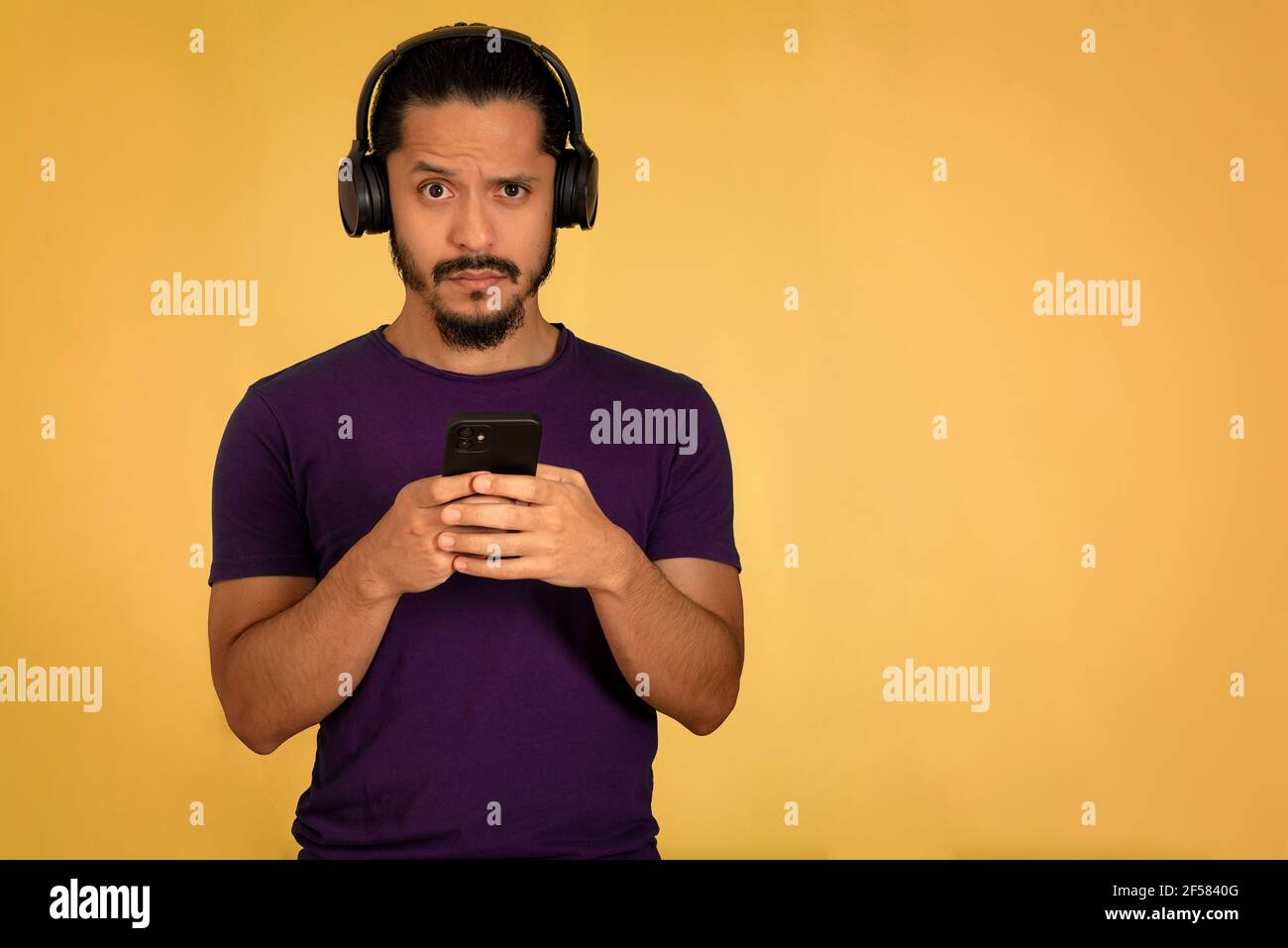 Young man with funny face listening music using headphones and playing ...