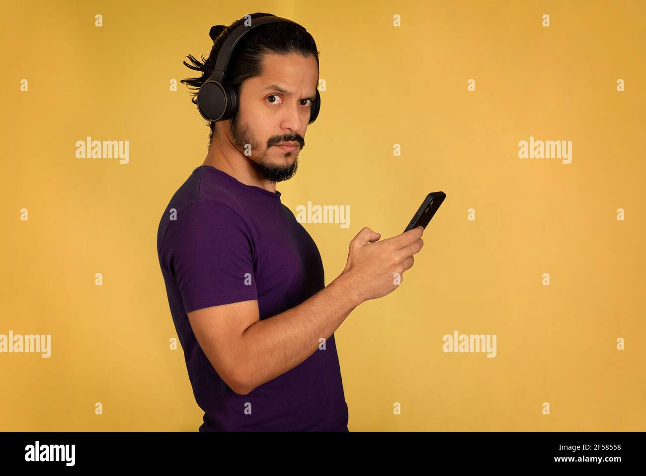 Young man with funny face listening music using headphones and playing ...