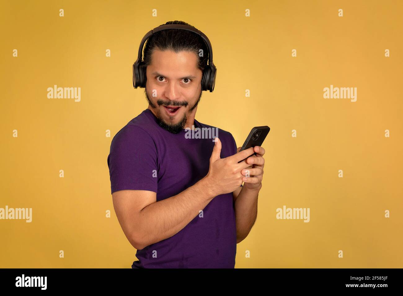 Young man with funny face listening music using headphones and playing ...