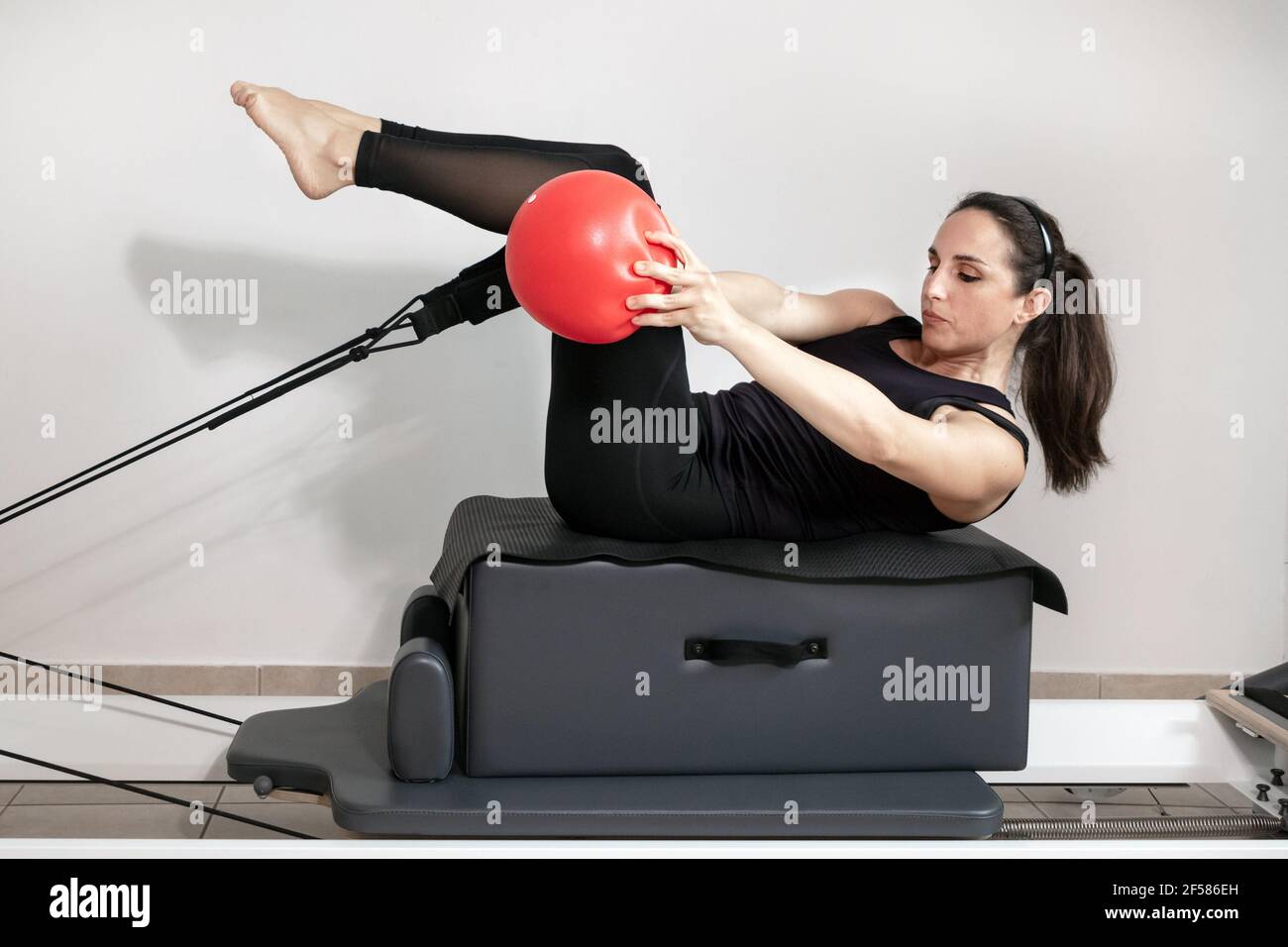 A woman doing pilates exercises on a reformed bed Stock Photo - Alamy