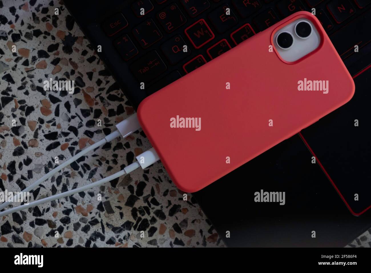 Red mobile phone charging with notebook computer Stock Photo - Alamy