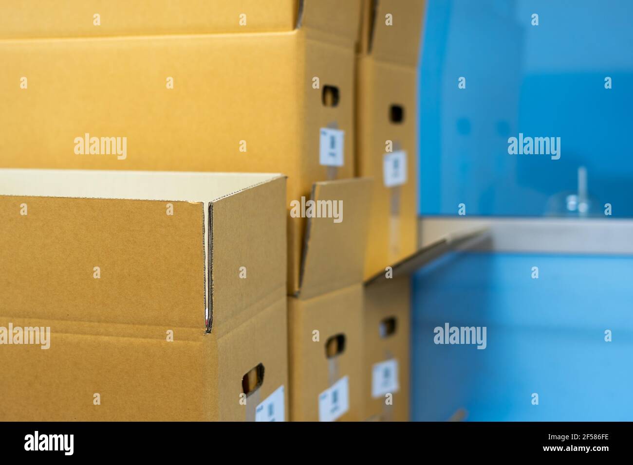 Pile or Stack of brown boxes in a blue office Stock Photo - Alamy