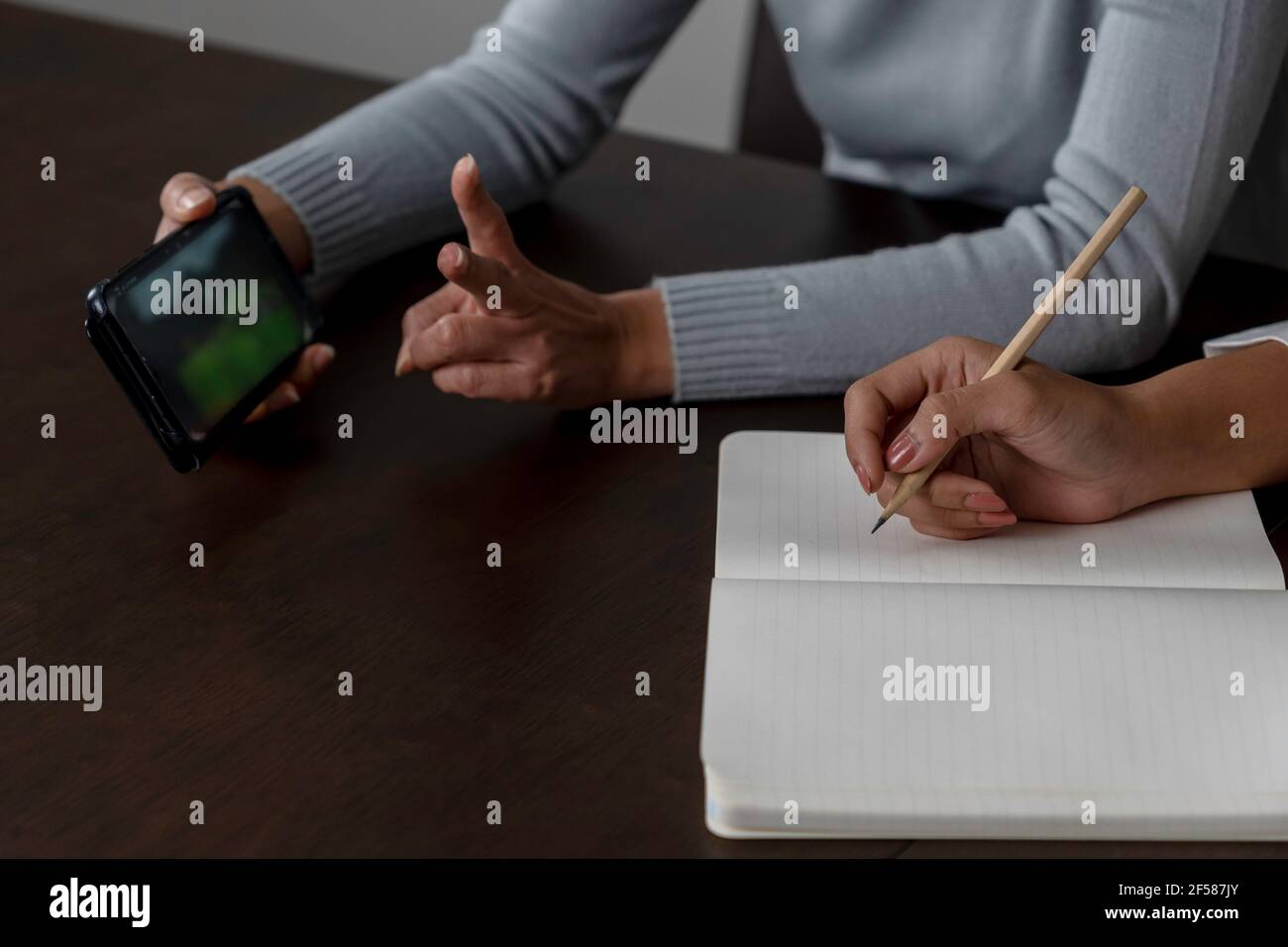 Female secretary holds a pencil to use information from a mobile phone ...