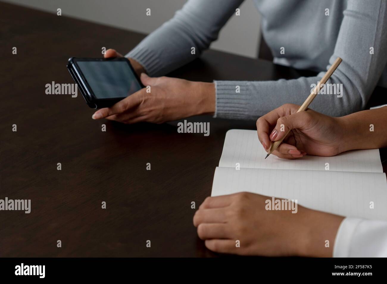 Female secretary holds a pencil to use information from a mobile phone ...