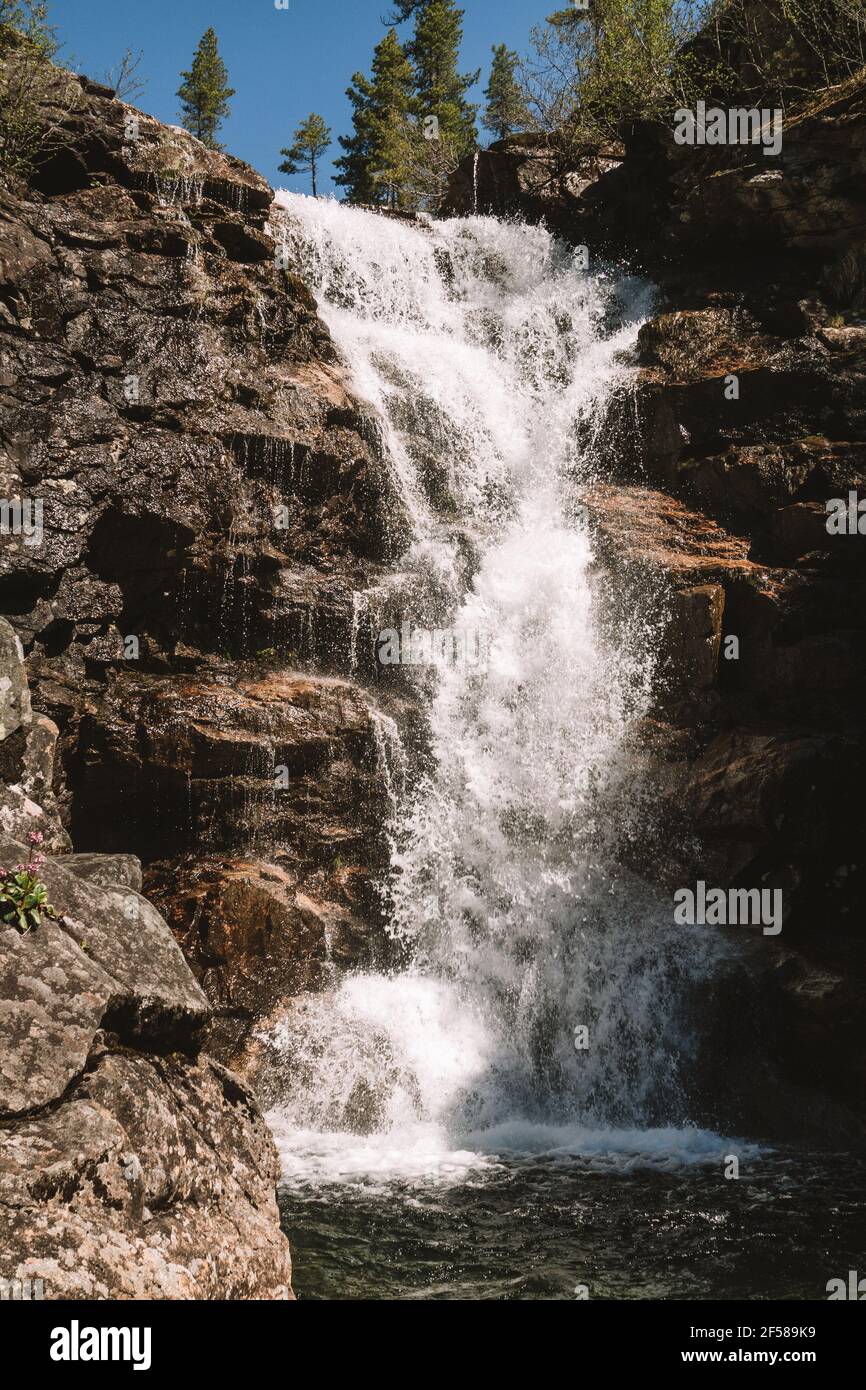 A picturesque waterfall flowing from a mountain gorge. One of the six ...