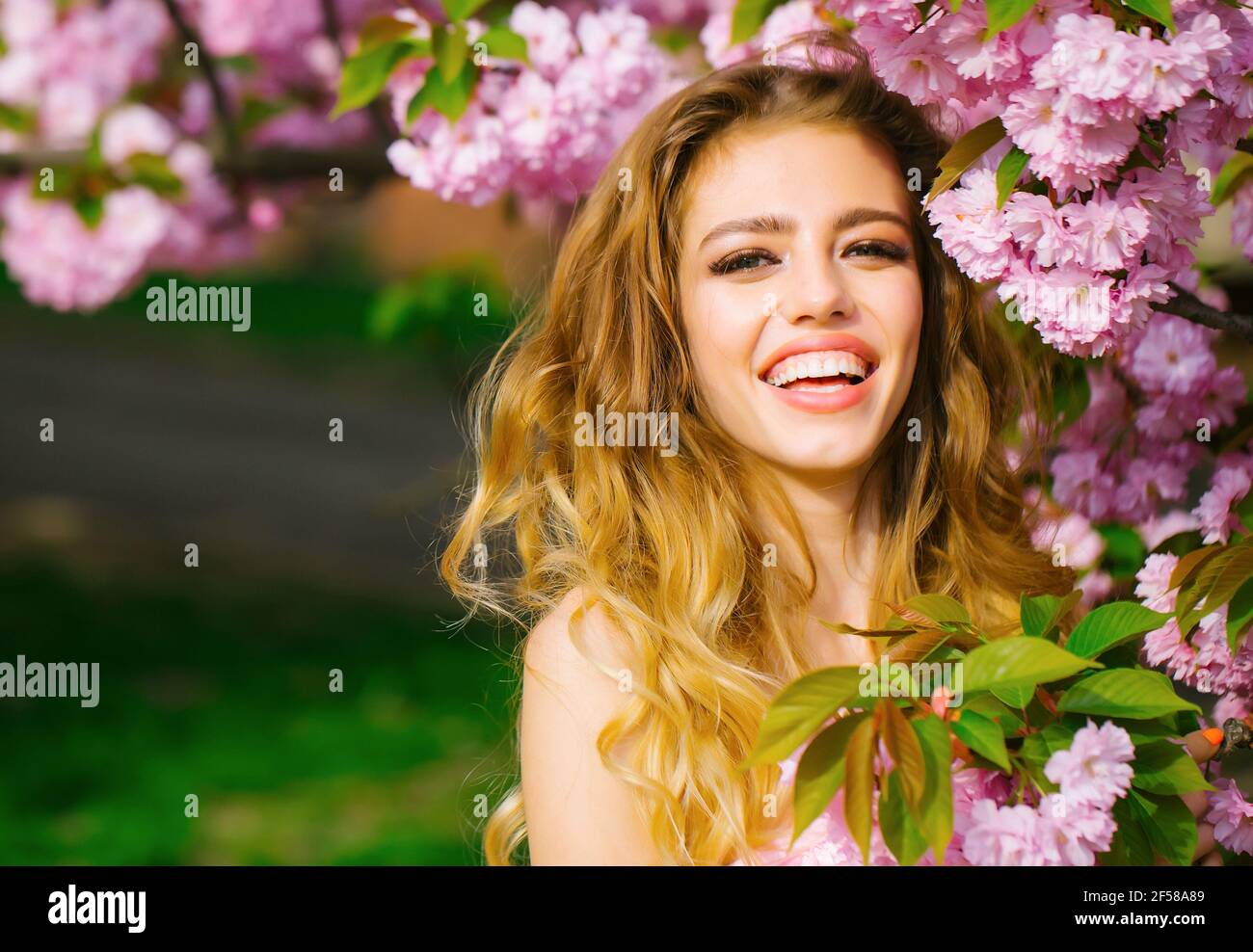 Pretty woman in pink blossom park. Happy young girl with smiling face ...
