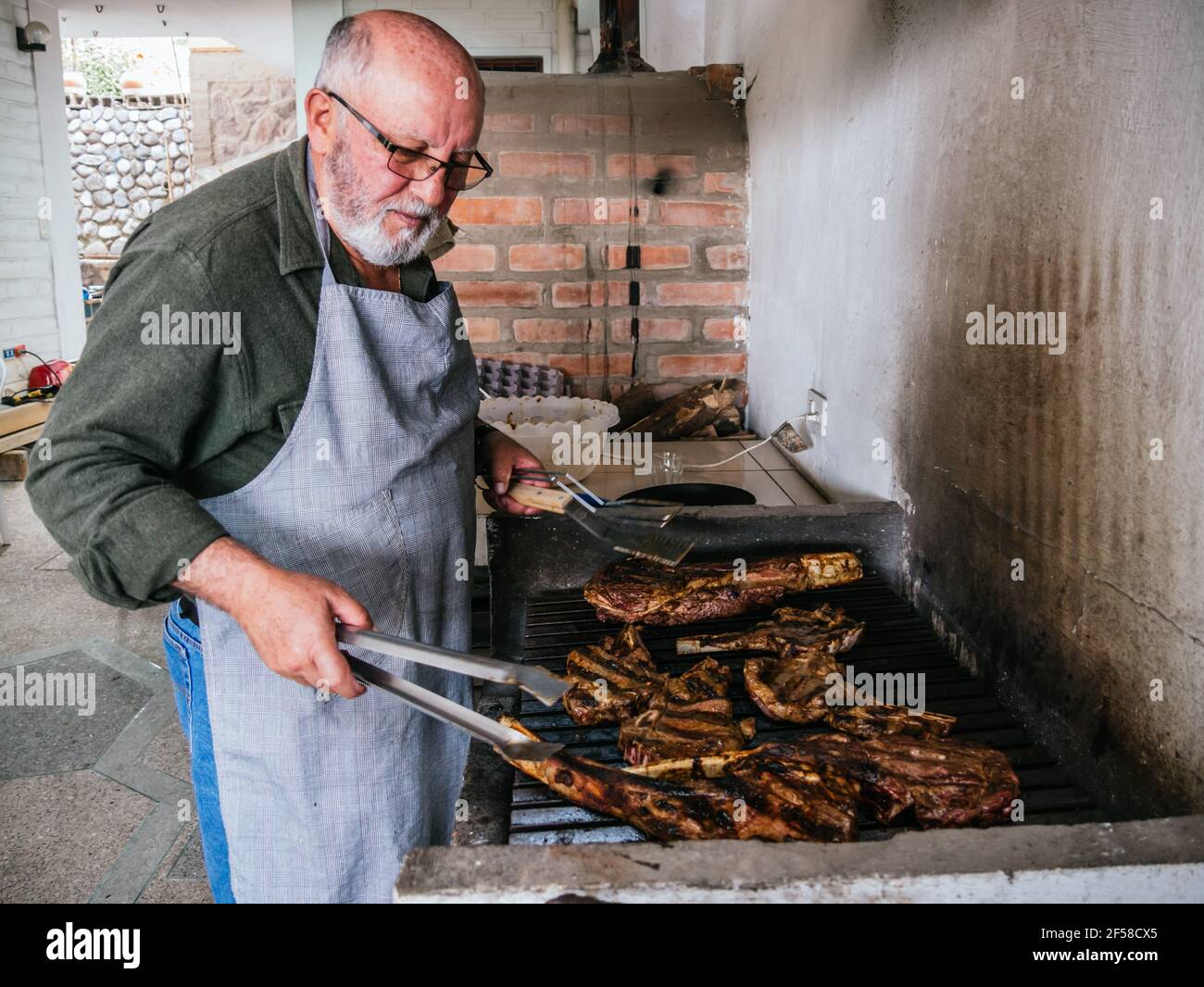 Ol man cooking Tomahawk rib beef steak on hot black grill Stock Photo ...