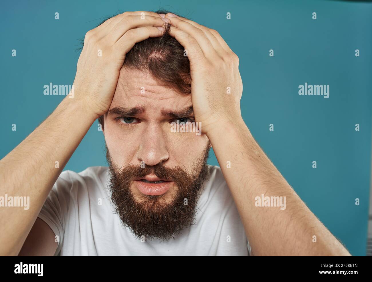 A man on a blue background is touching his head with his hands Stock ...