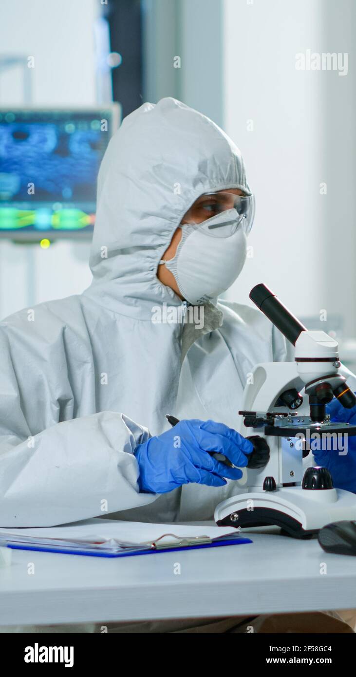 Medical research scientist conducting DNA experiments under microscope ...
